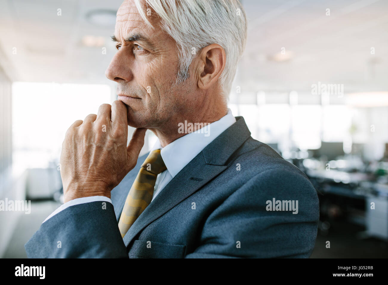Side view shot of mature businessman thinking with hand on chin ...