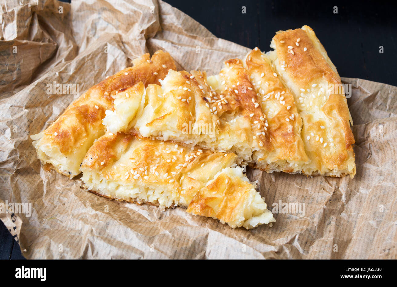 Cheese pie covered with sesame on wrapping paper Stock Photo - Alamy