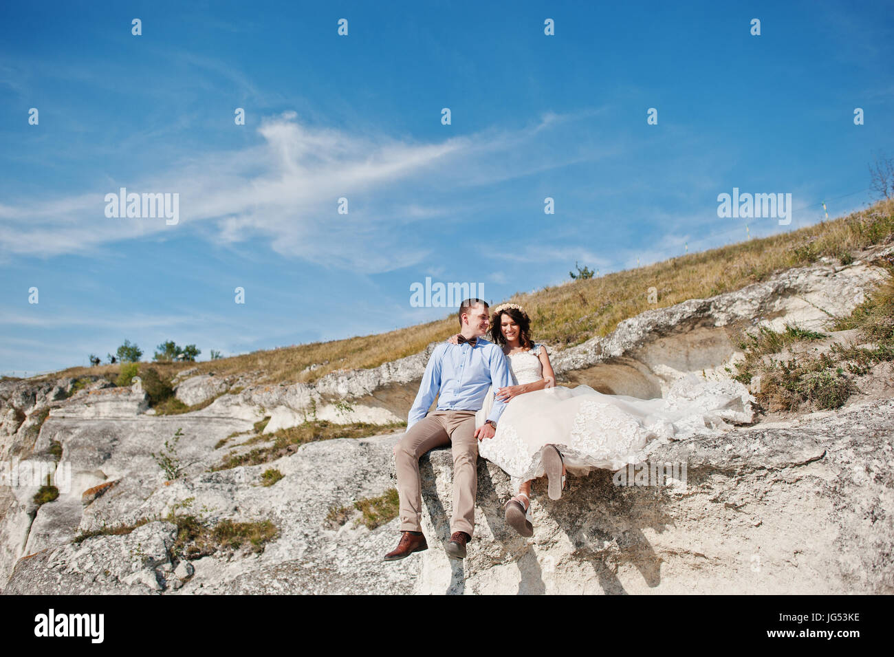 Stunning young wedding couple sitting on the edge of the cliff with a ...