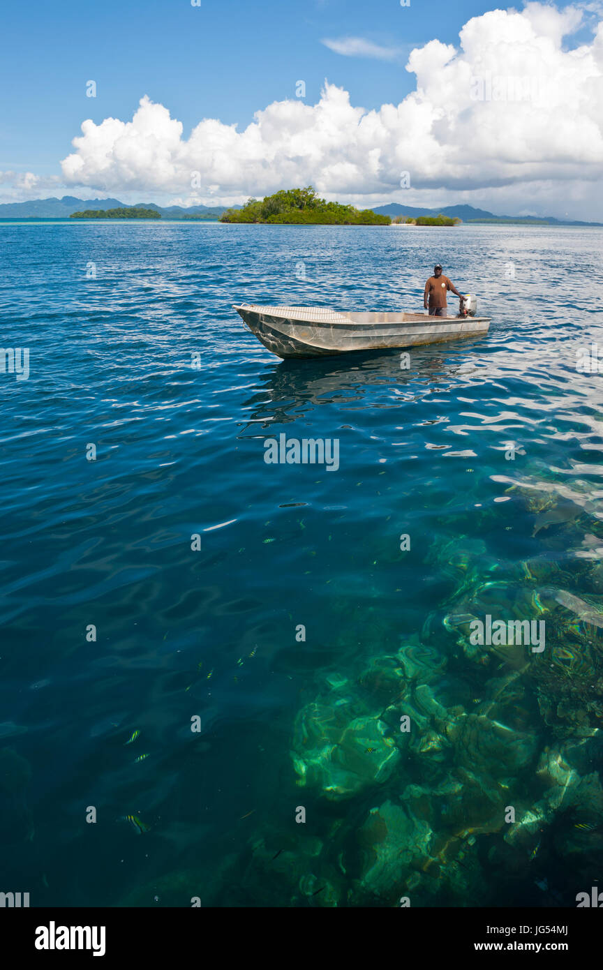 Man sitting in his motor boat in the clear waters of the Marowo Lagoon ...