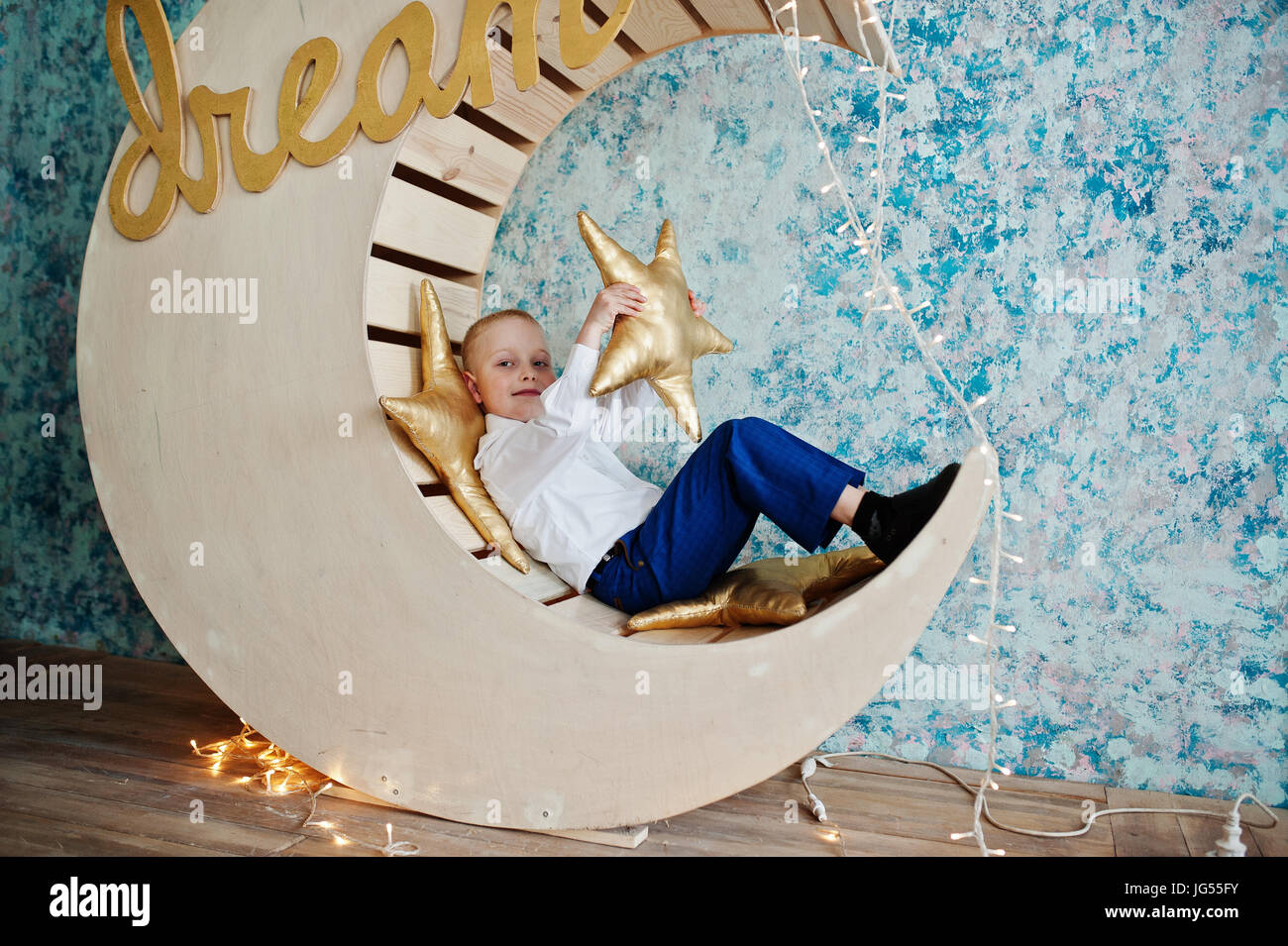 Cute small handsome boy posing on artificial moon decoration while ...