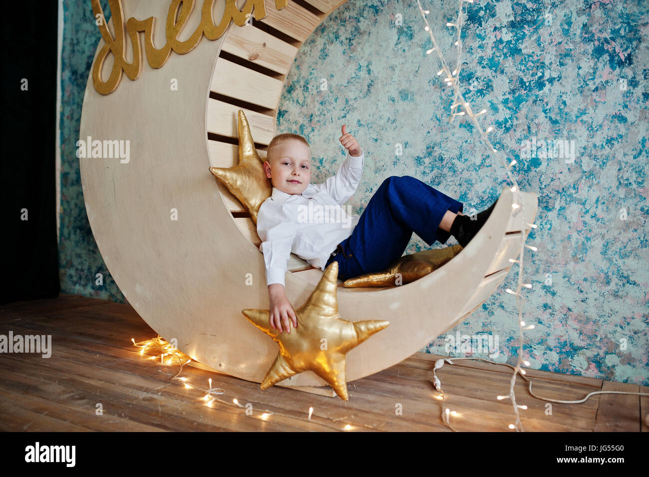 Cute small handsome boy posing on artificial moon decoration while ...