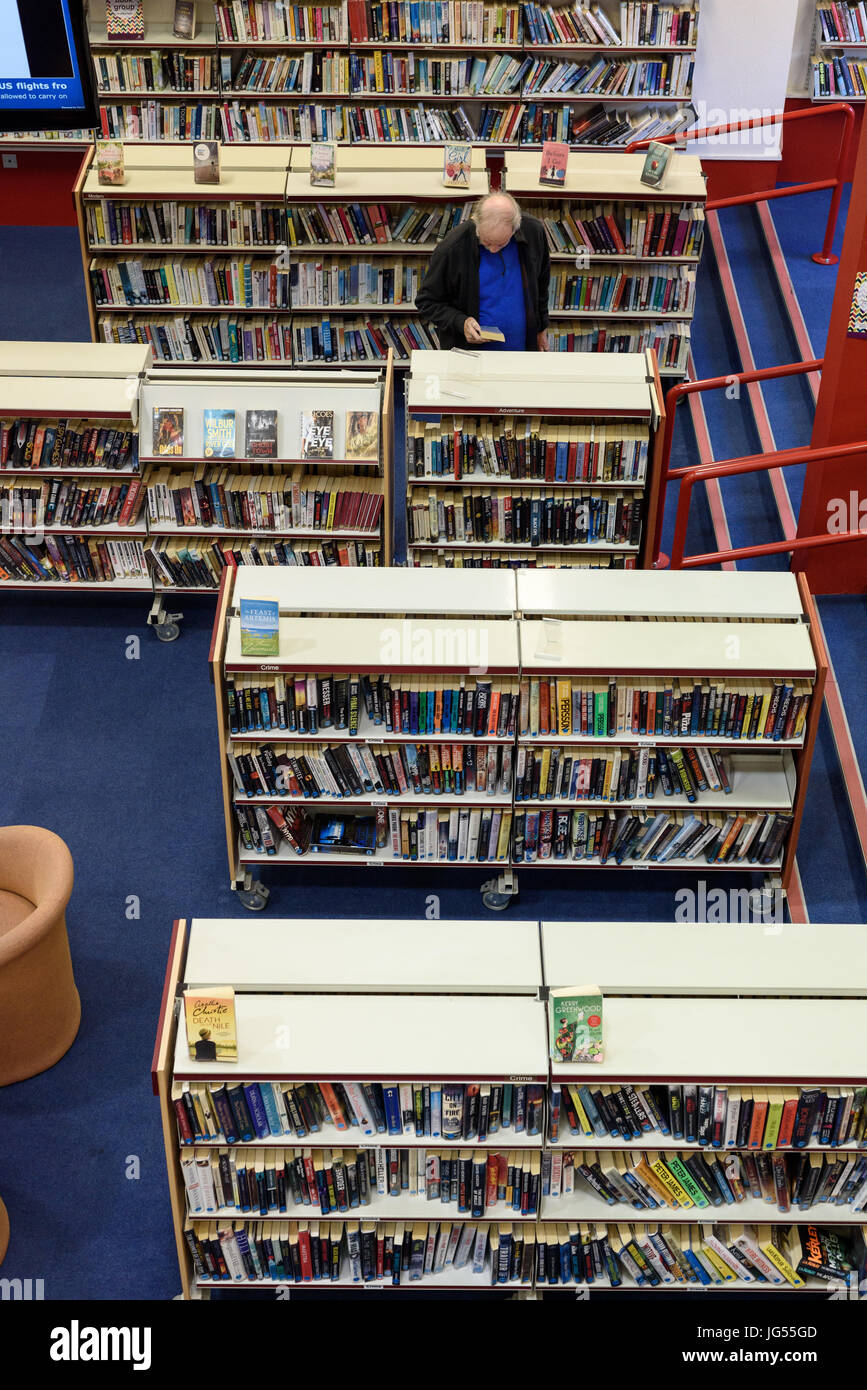 Man choosing books from bookshelves in a free public library Stock ...