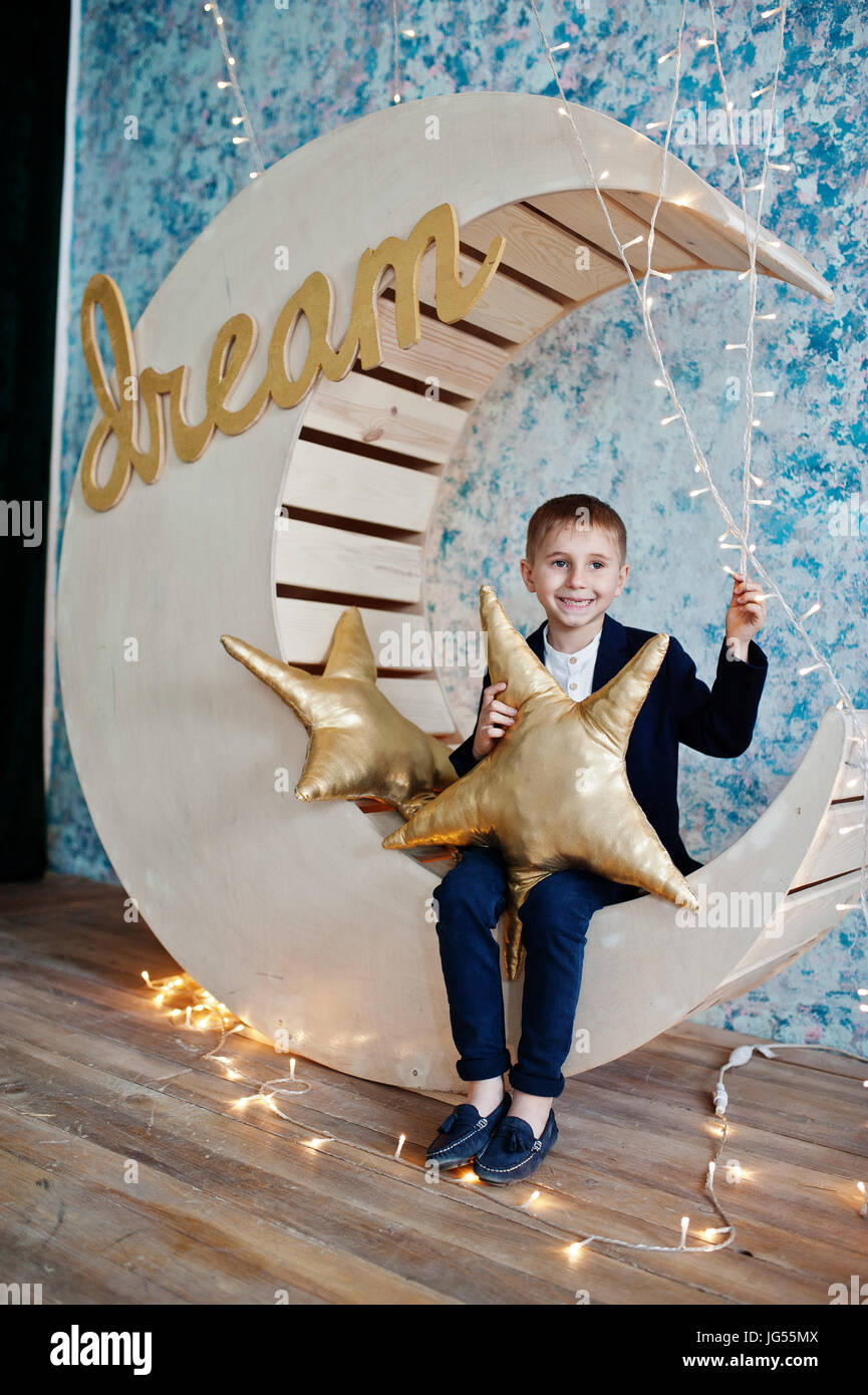 Cute small handsome boy posing on artificial moon decoration while ...