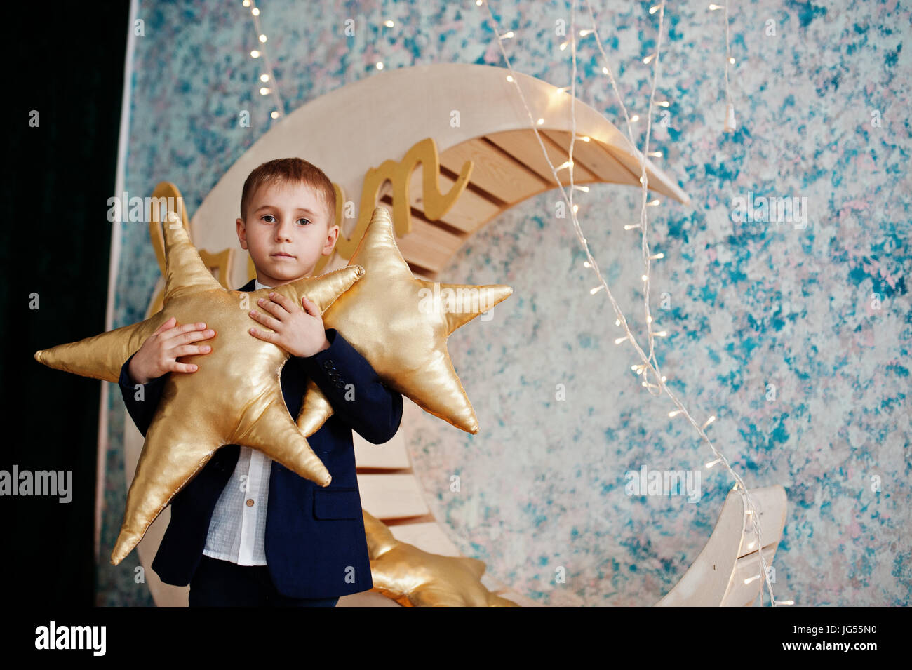 Cute small handsome boy posing on artificial moon decoration while ...