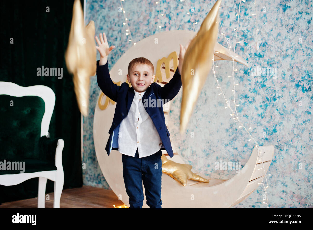 Cute small handsome boy posing on artificial moon decoration while ...