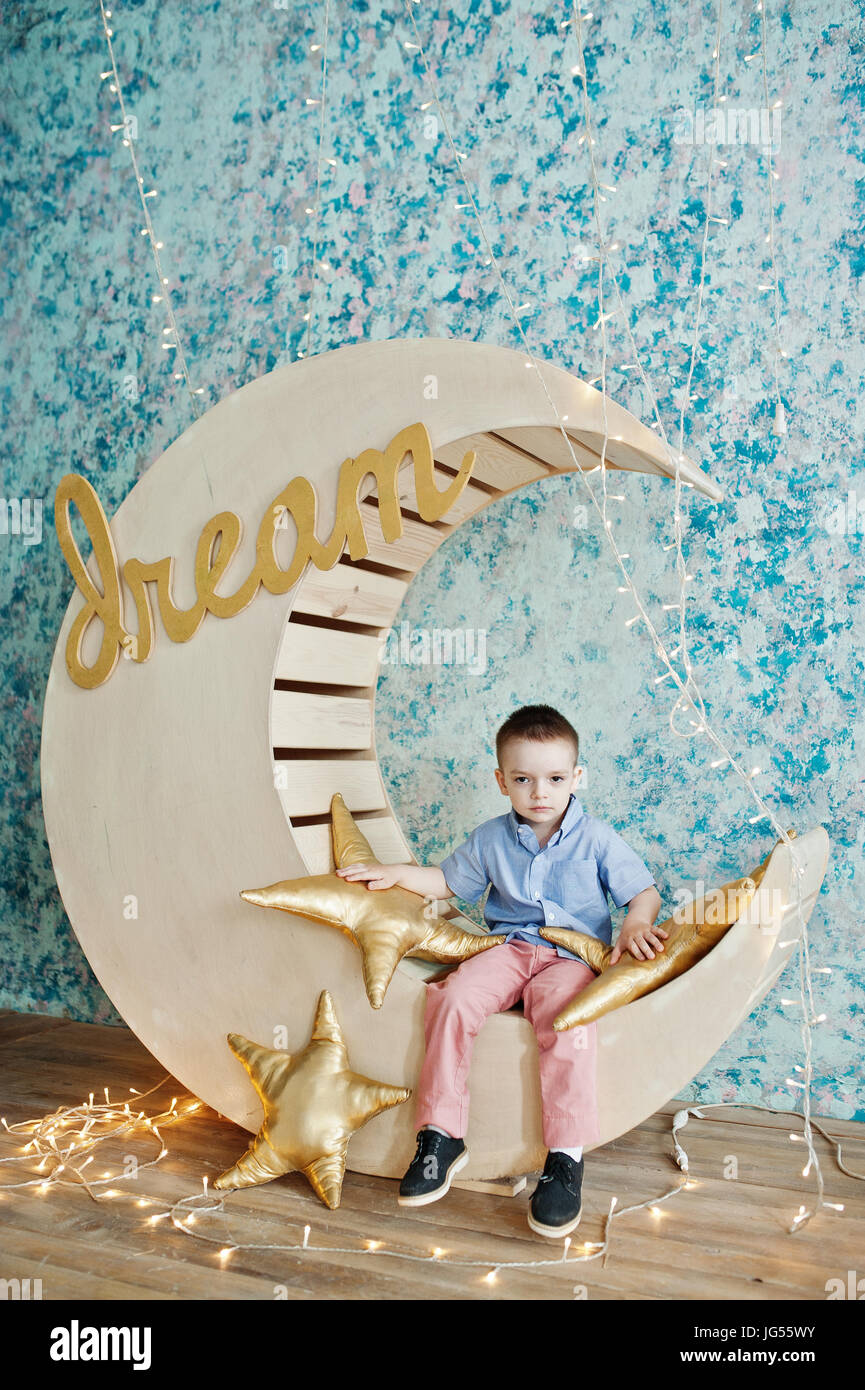 Cute small handsome boy posing on artificial moon decoration while ...