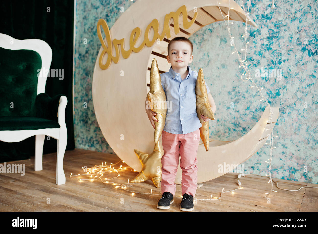 Cute small handsome boy posing on artificial moon decoration while ...