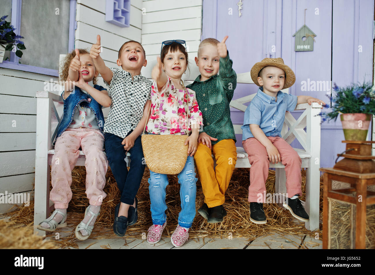 Preschool kids posing outside the house with straw in the rural area ...