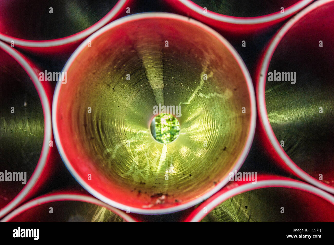 Tunnel view through stacked pipes with internal reflection and light at ...