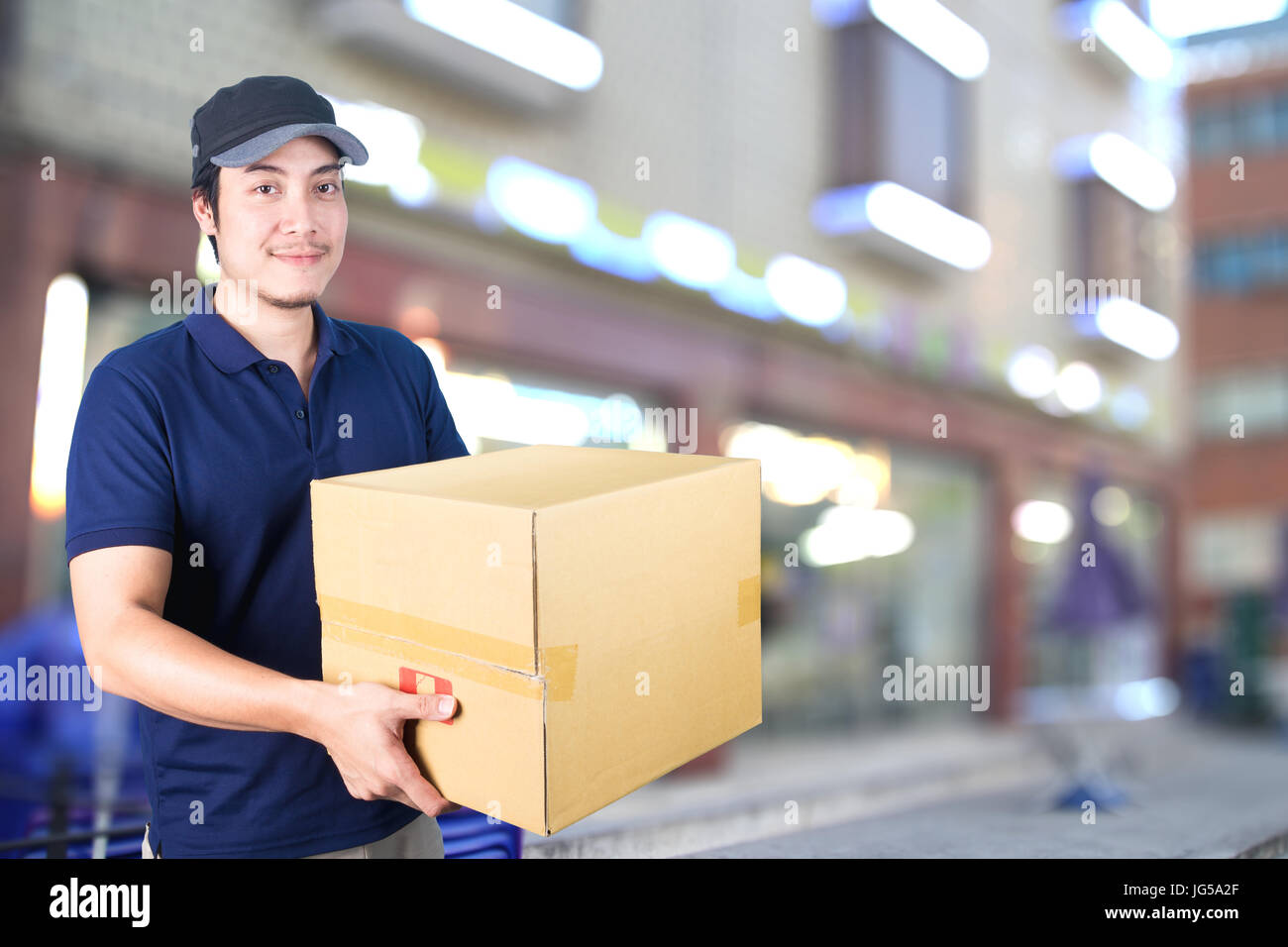 Asian smile Delivery man with cardboard box in hand standing on blurred ...