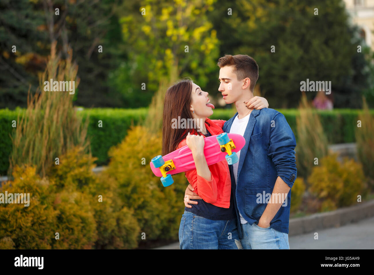 Teenagers on a date. First love. Strong embrace. She holds a skateboard ...