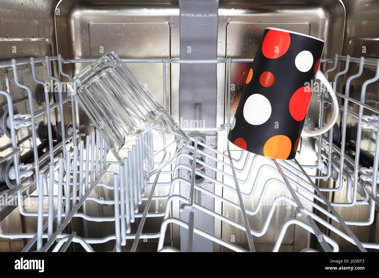 Wet dishwasher interior with one cup and glass. Washing kitchen ...