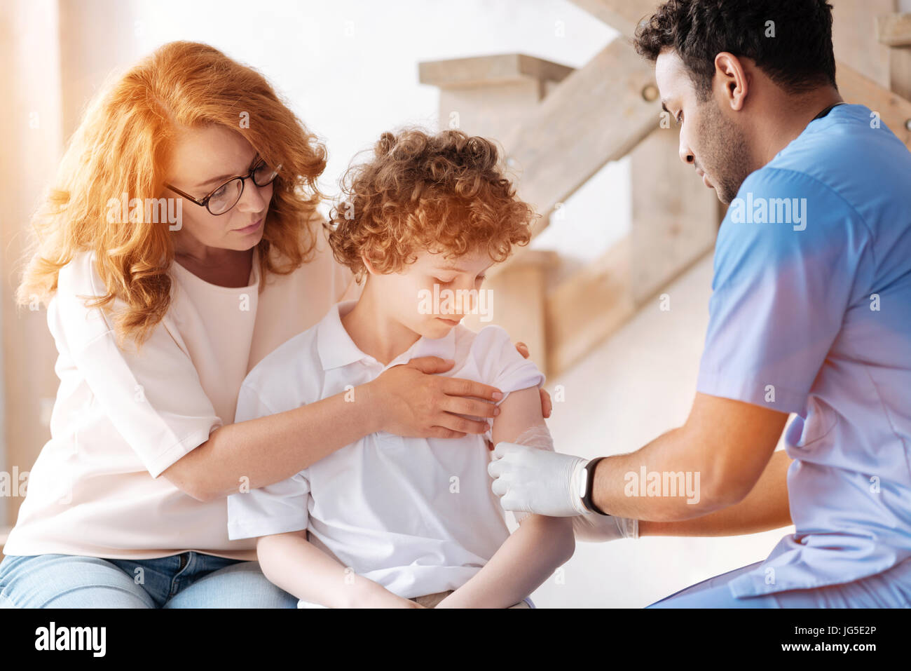 Attentive medical worker winding bandage around left arm Stock Photo ...