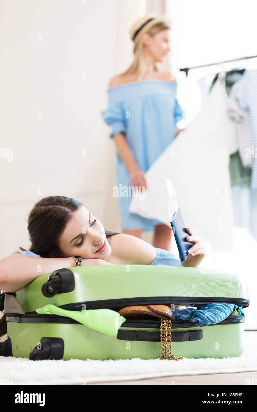 Smiling Young Woman Leaning On Suitcase And Holding Passports And