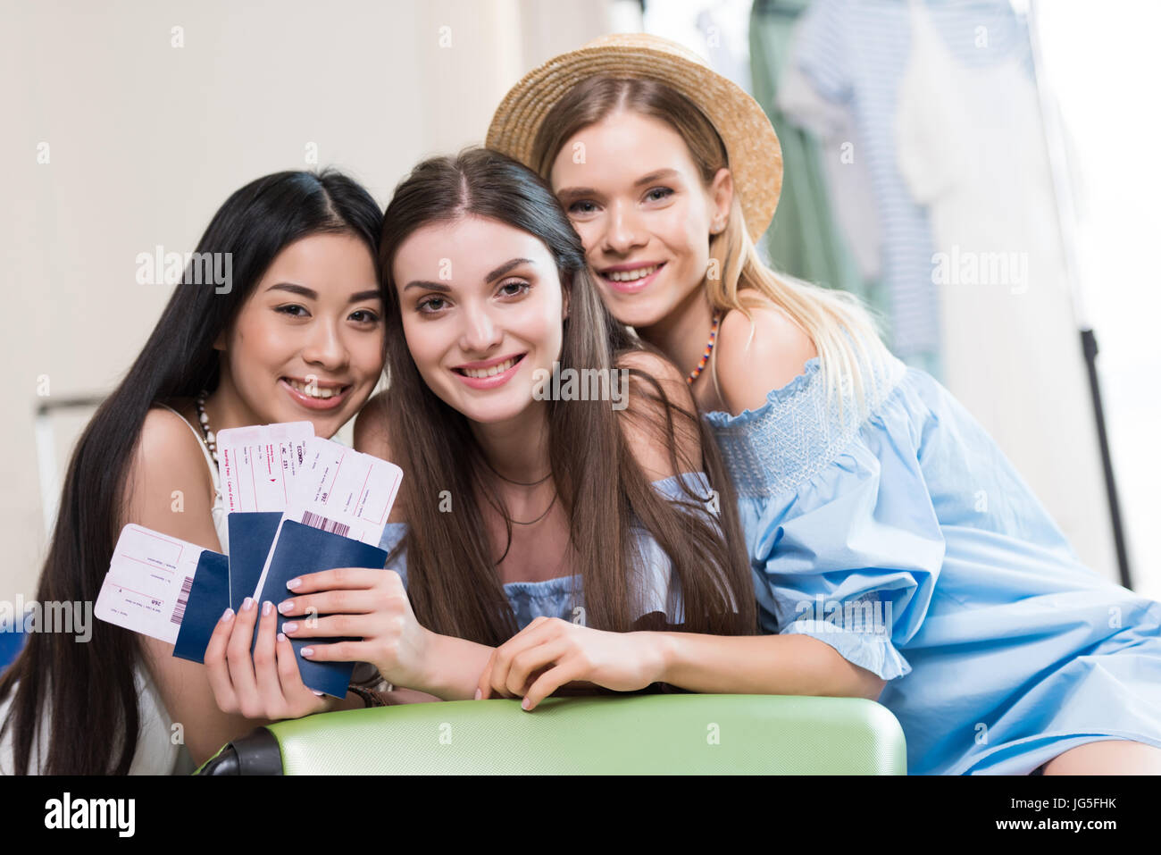 Three Young Smiling Women Holding Passports And Tickets While Packing