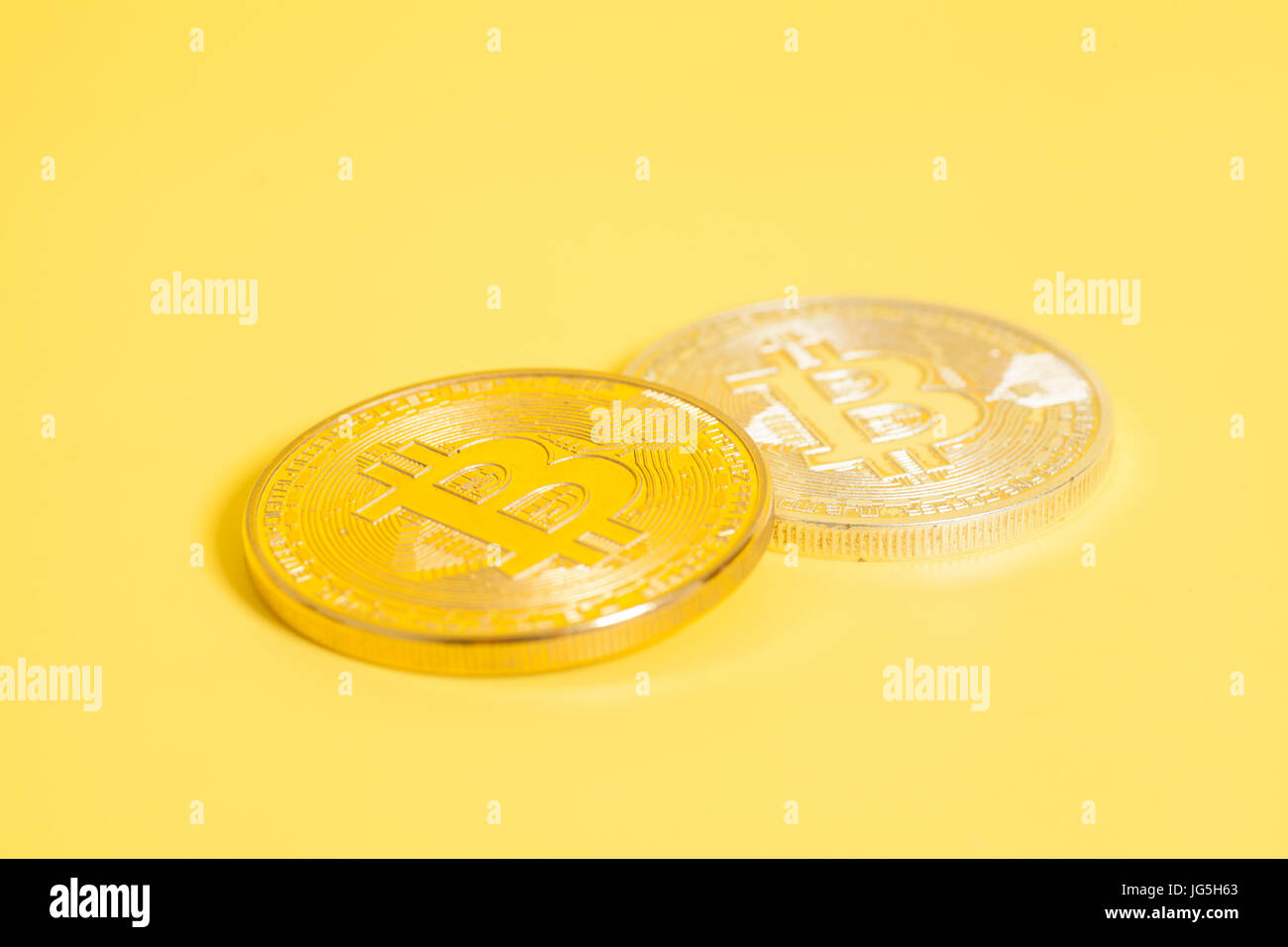 Two bitcoins silver and gold on yellow background Stock Photo - Alamy