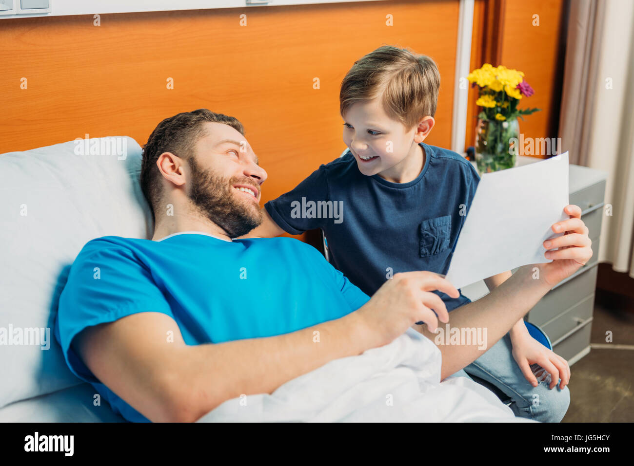 little son showing sick father his drawings at ward, hospital patient ...