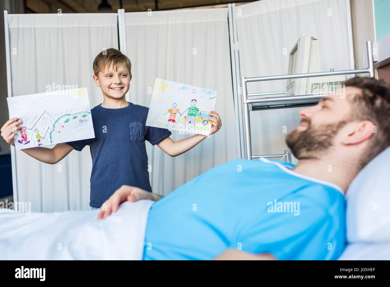 little son showing sick father his drawings at ward, dad and son Stock ...