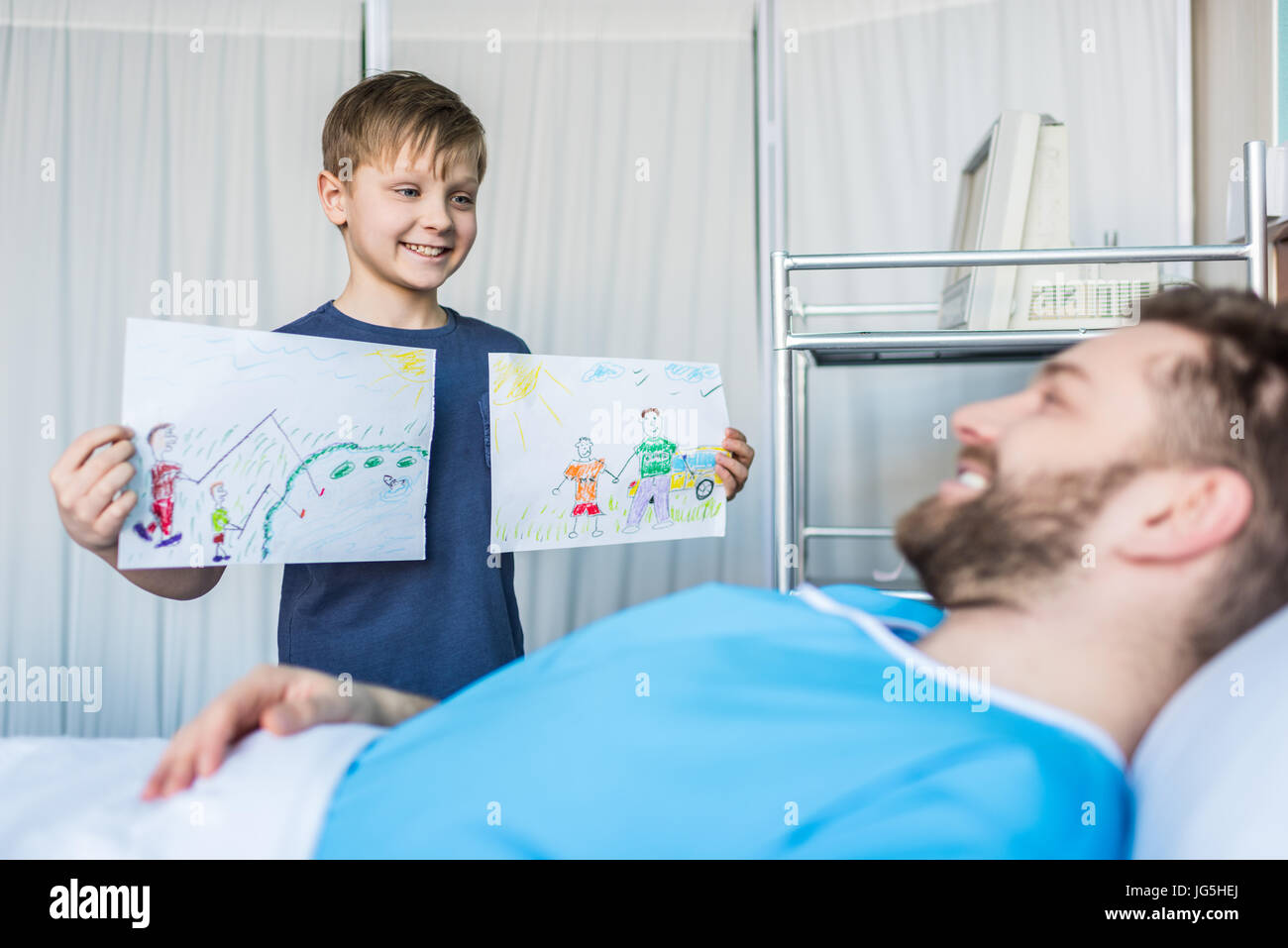 little son showing sick father his drawings at ward, dad and son Stock ...
