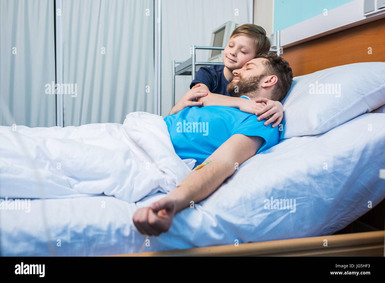 father with son embracing while laying on hospital bed at ward, dad and ...