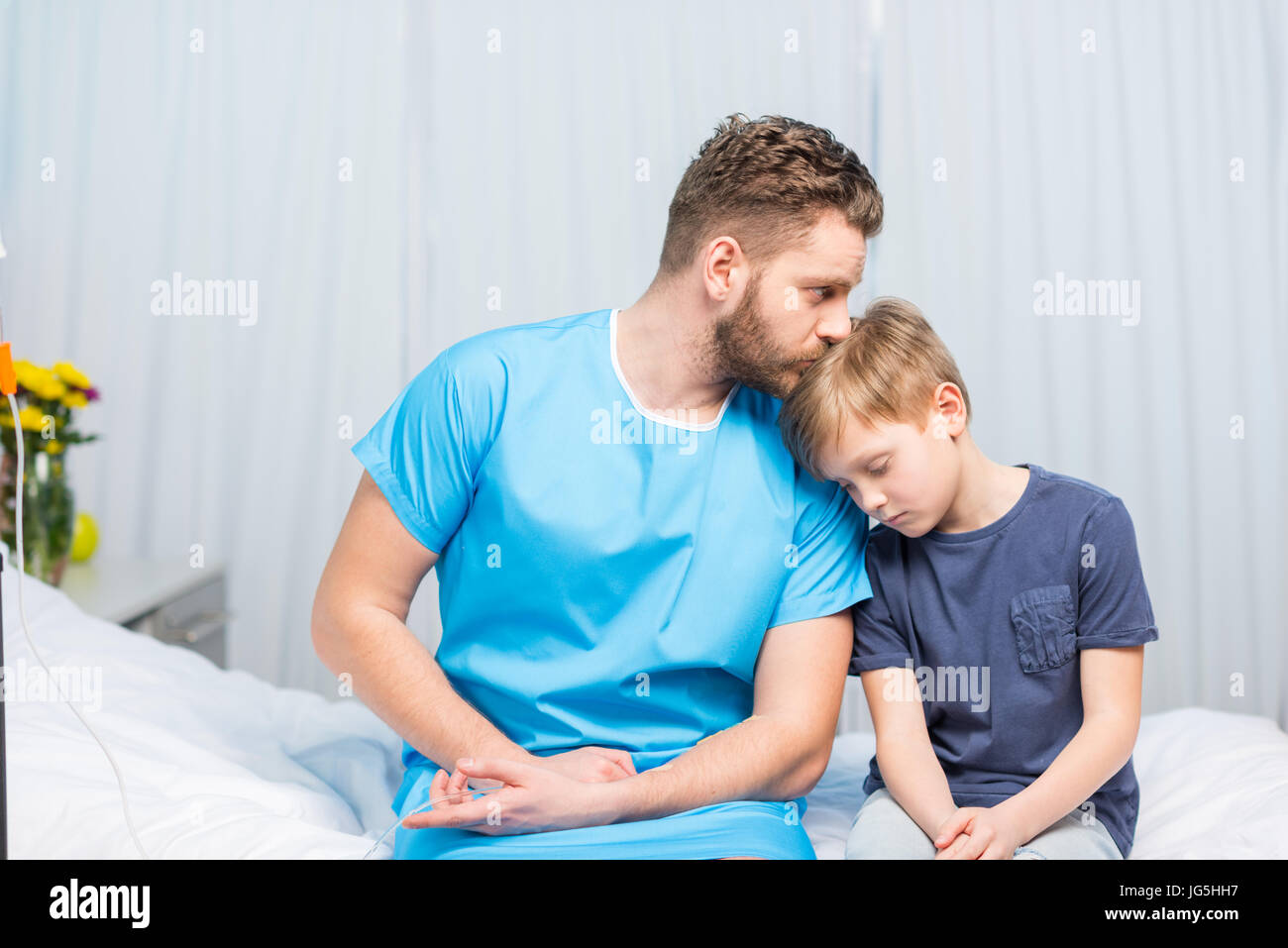 Sick father and upset son sitting together on hospital bed, dad and son ...
