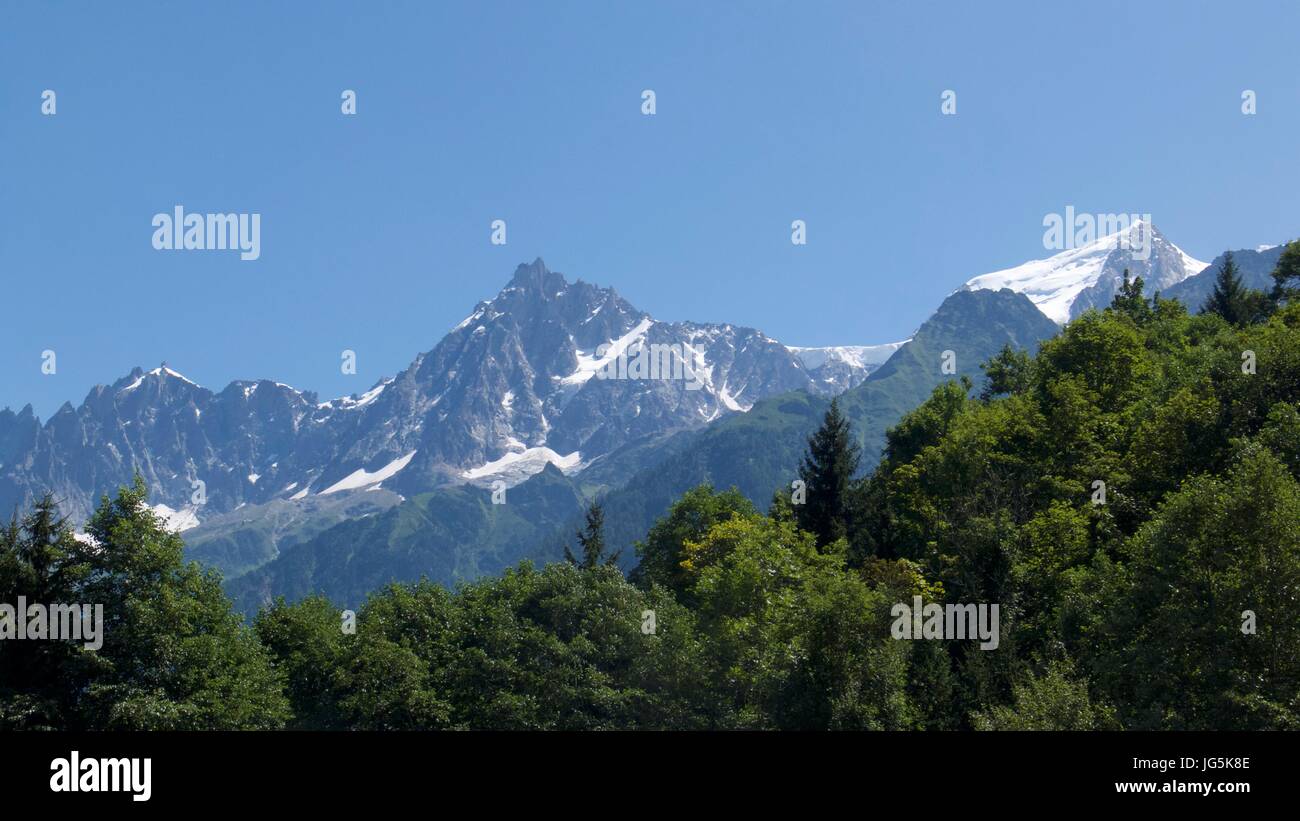 Elevated landscape view of snow capped French Alps over tree tops, Les ...