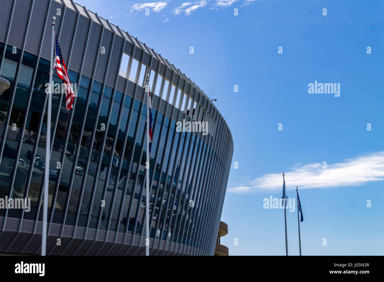 Modern rounded building exterior with flags out front Stock Photo - Alamy