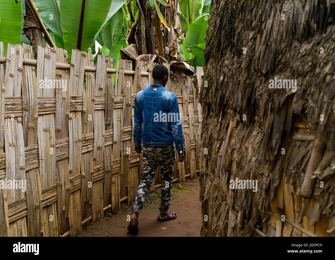 Man passing along a traditional dorze house made of bamboo and enset ...