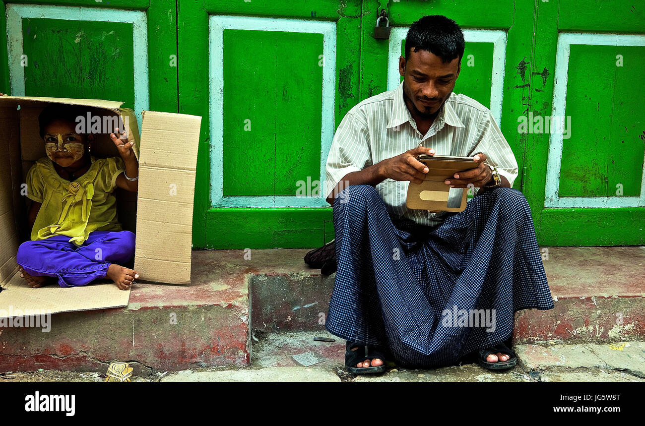 A young girl of south-asian origins sits inside a cardboard box in a ...