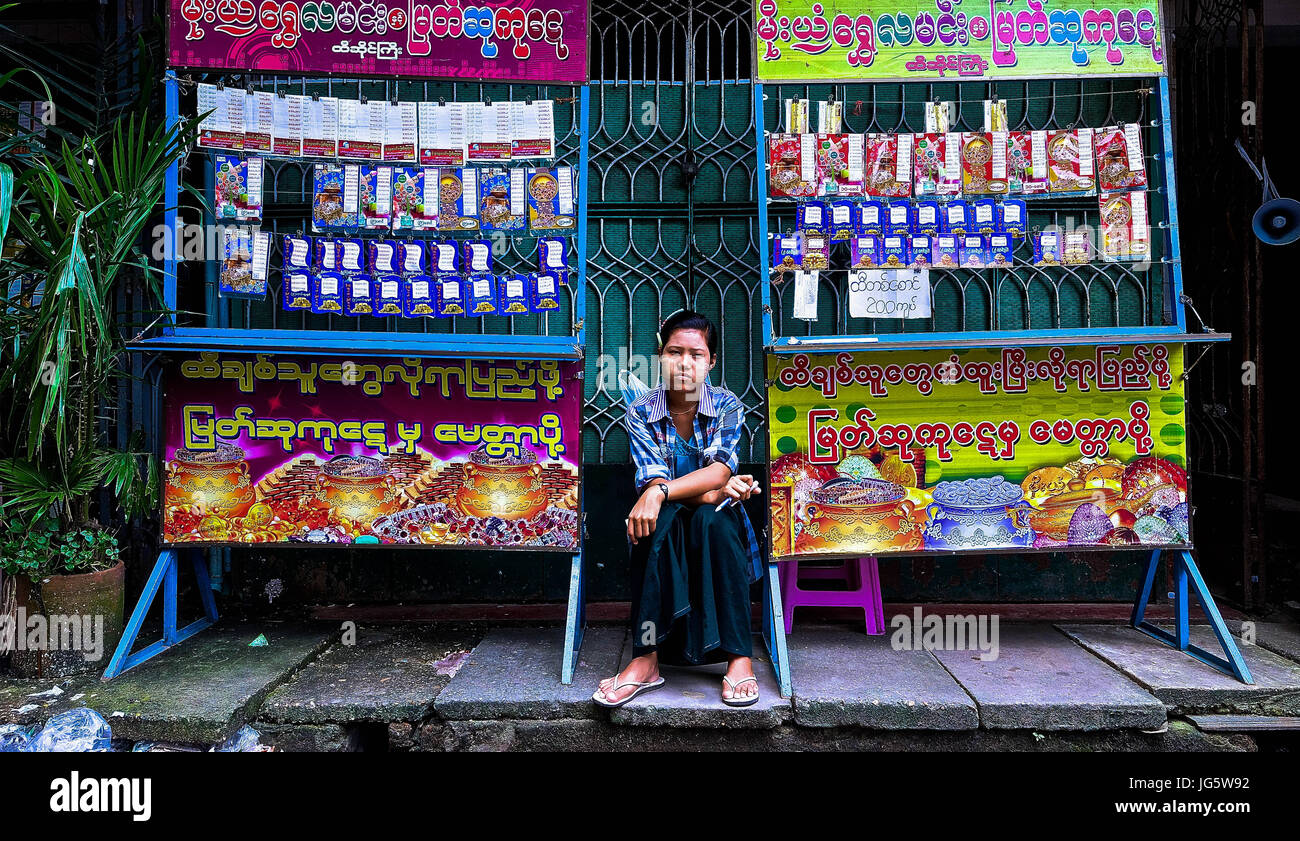 A female lottery ticket seller sits at her stall in downtown Yangon ...