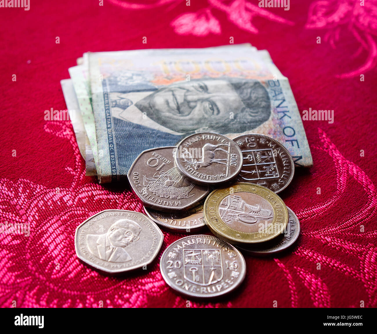 Mauritius Rupee (MUR) notes and coins with red background - close up ...