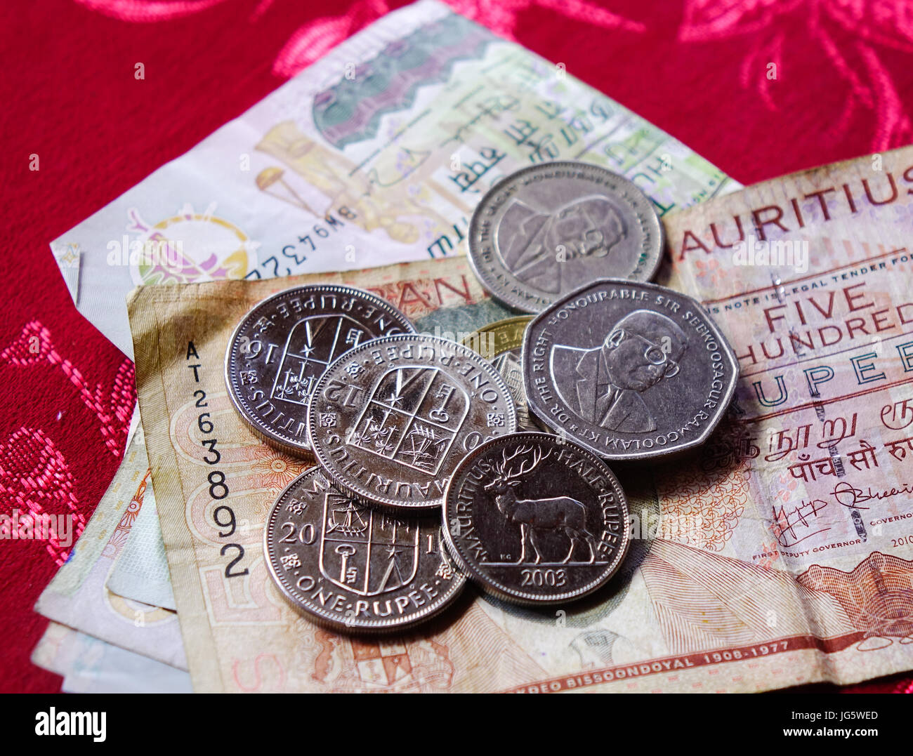 Mauritius Rupee (MUR) notes and coins with red background - close up ...
