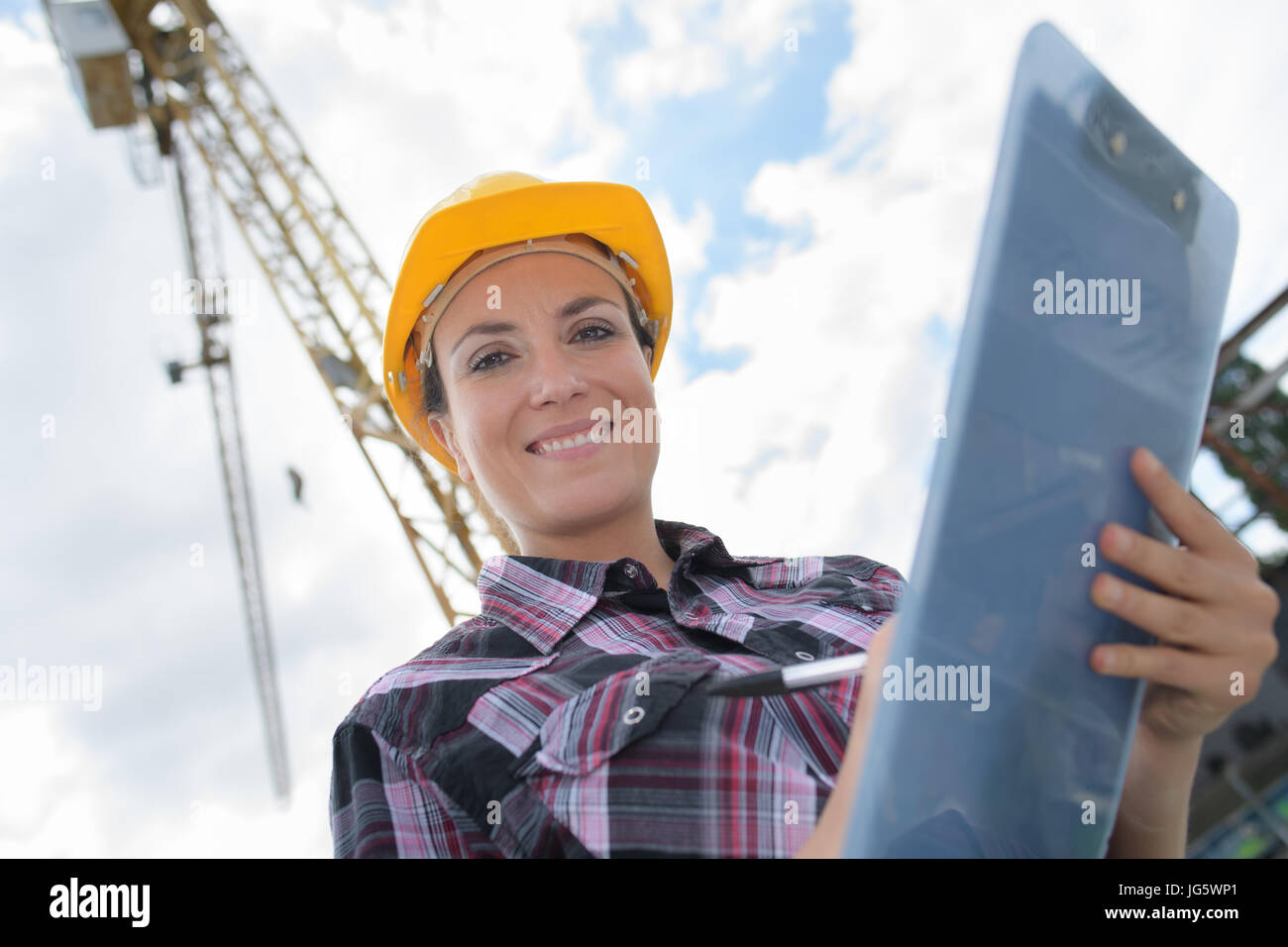 beautiful engineer similing and posing under crane at construction site ...
