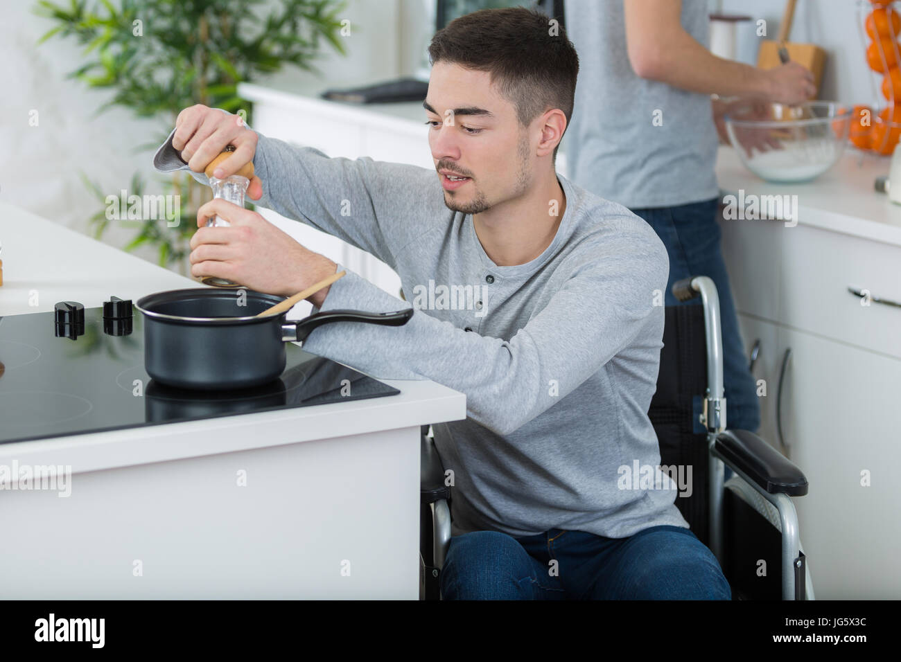 disabled young man in wheelchair is cooking in the kitchen Stock Photo ...