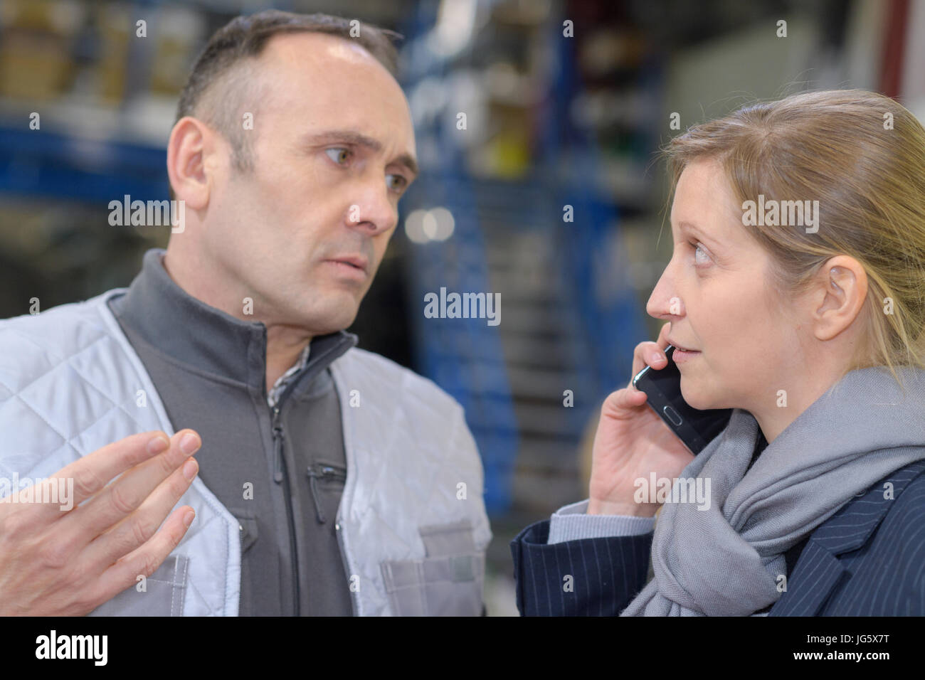 upset male worker talking to female colleague in warehouse Stock Photo ...