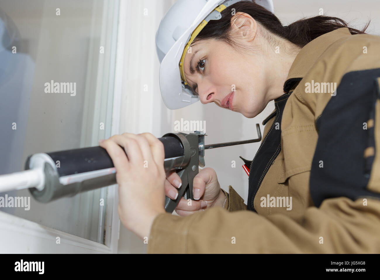 female construction worker caulking window with silicone glue Stock ...