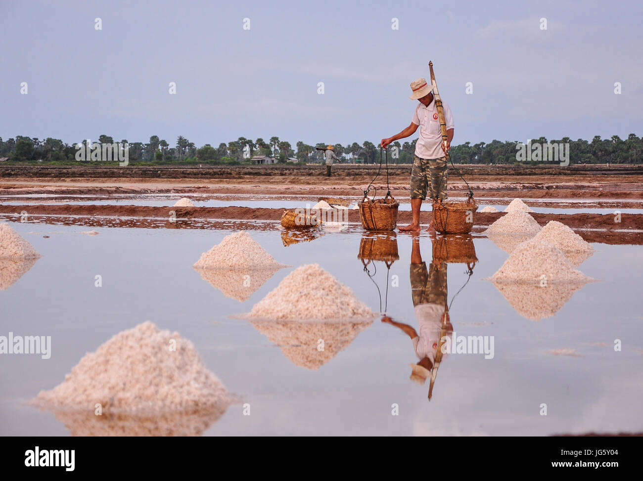 Kampot, Cambodia - Jan 25, 2012. A man harvesting salt on the field in ...