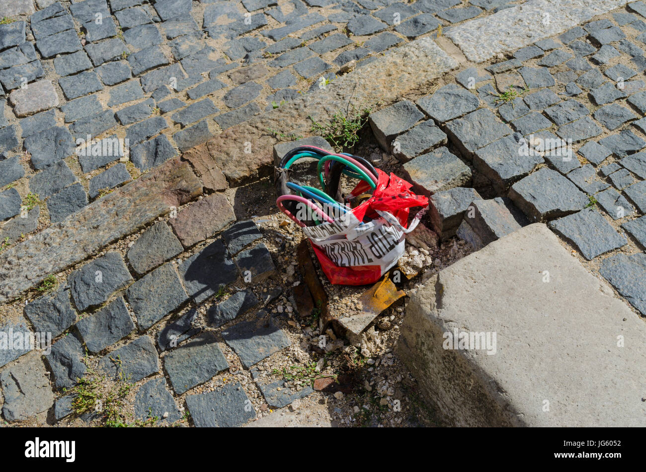Exposed and unprotected electrical wiring on a cobbled pavement or ...