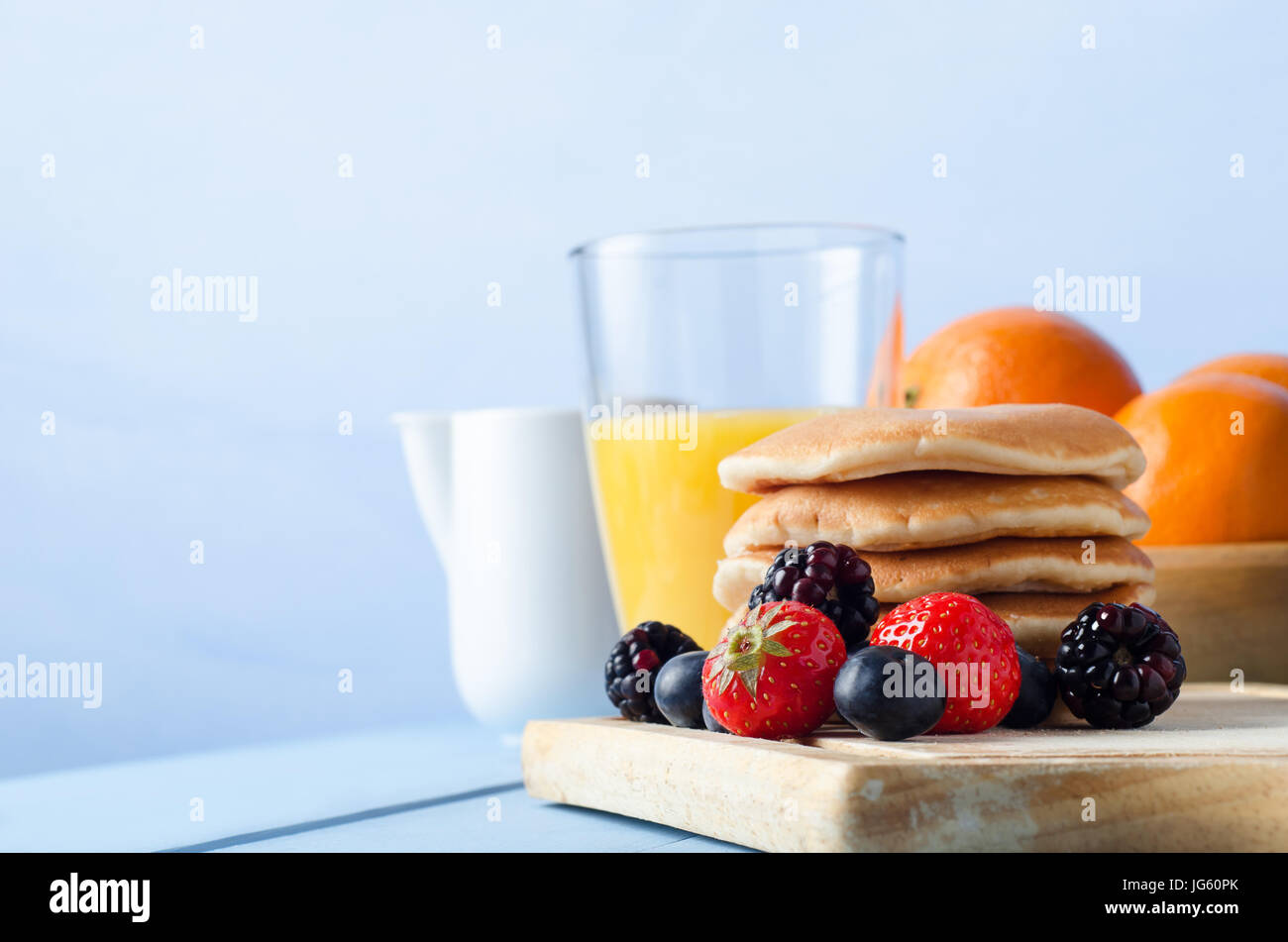 Breakfast table scene with Summer berry fruits and a stack of pancakes ...