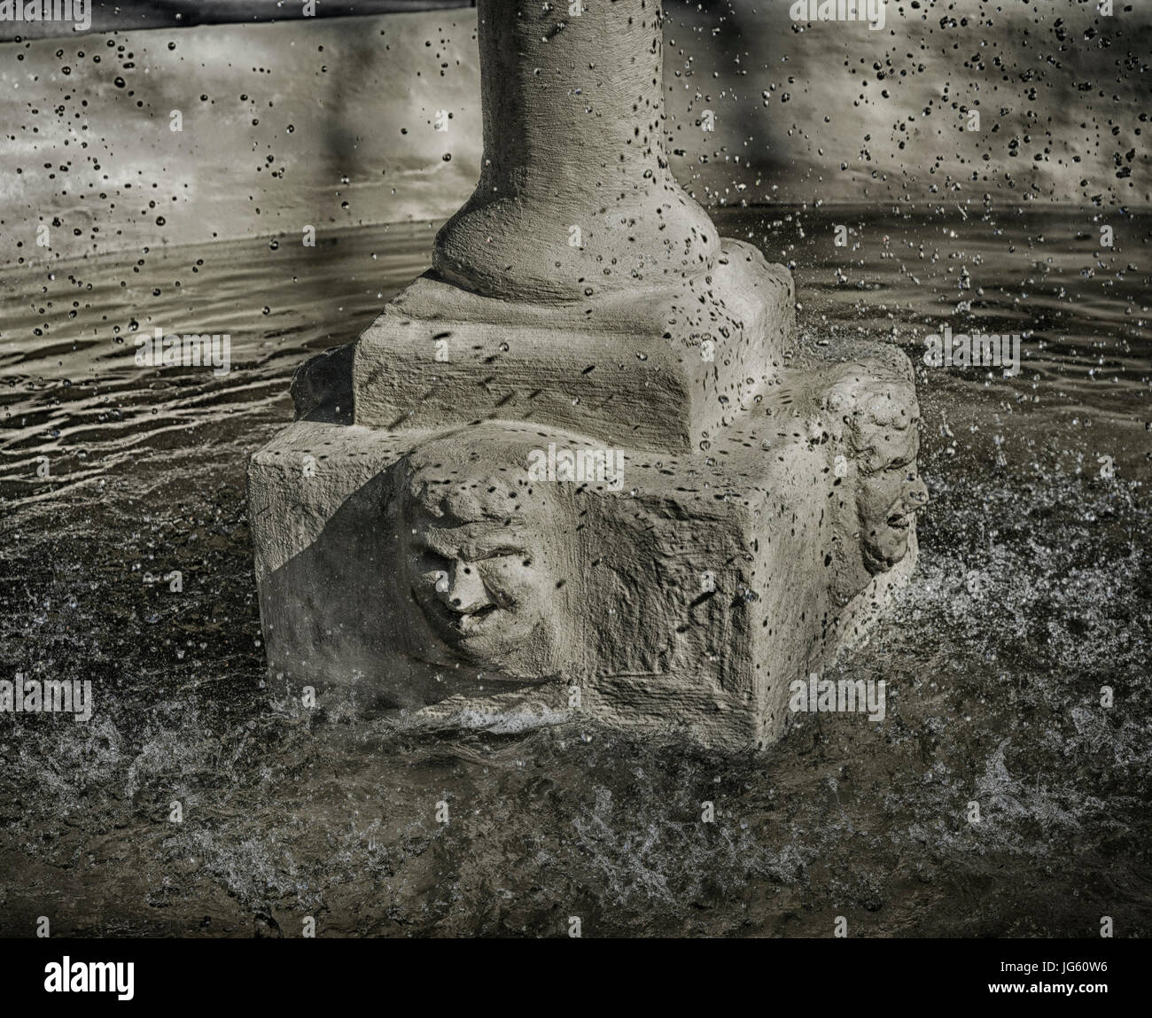 Faces sculpted at base of fountain with water falling around Stock ...