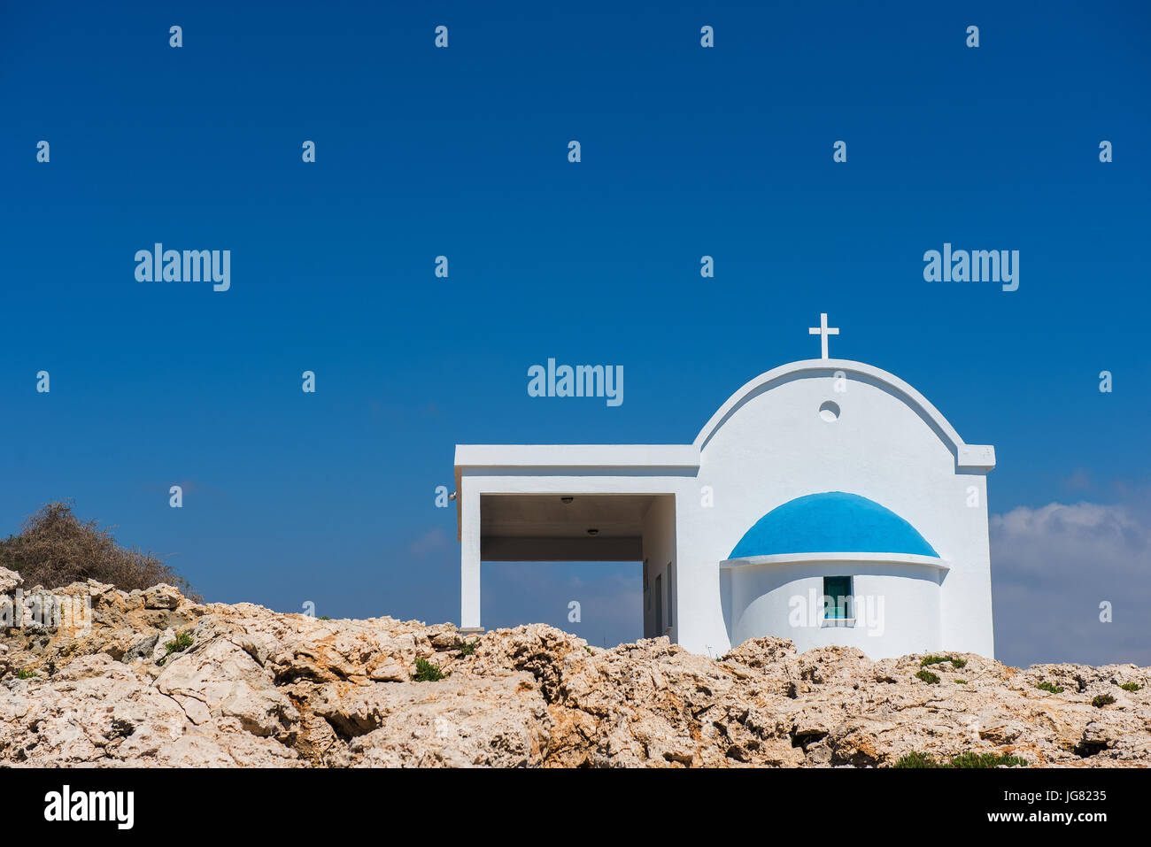 Traditional Greek white chapel with a blue roof on the seaside. Agioi ...