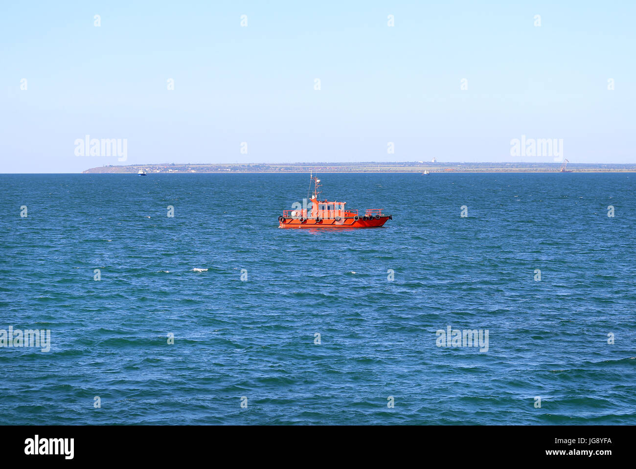 Beautiful red boat floating in blue sea Stock Photo - Alamy