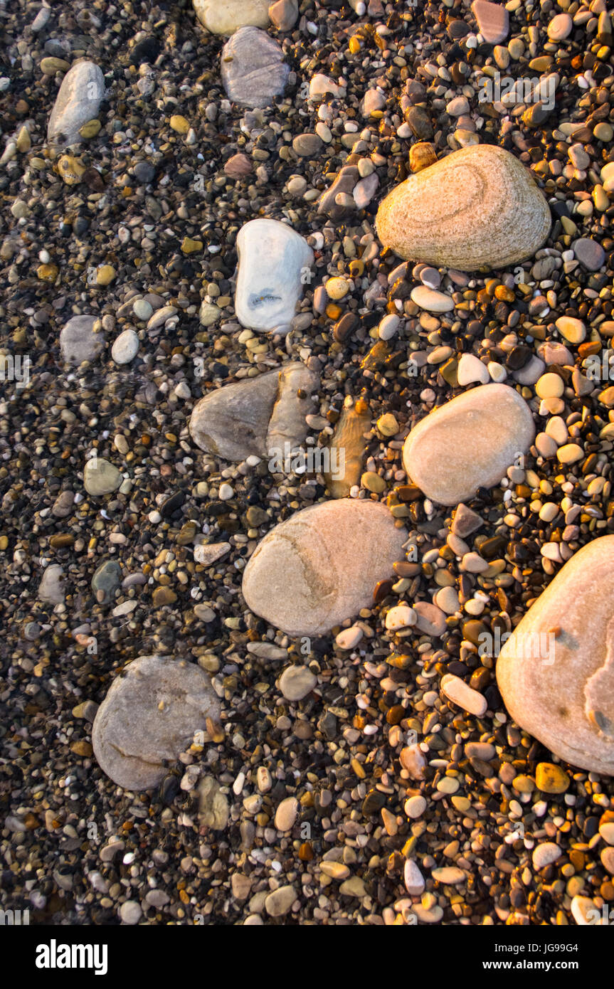 sea pebble beach with multicoloured stones, transparent waves with foam ...