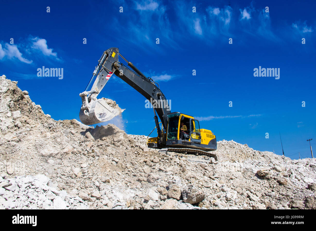 the excavator digging clay on blue sky background Stock Photo - Alamy