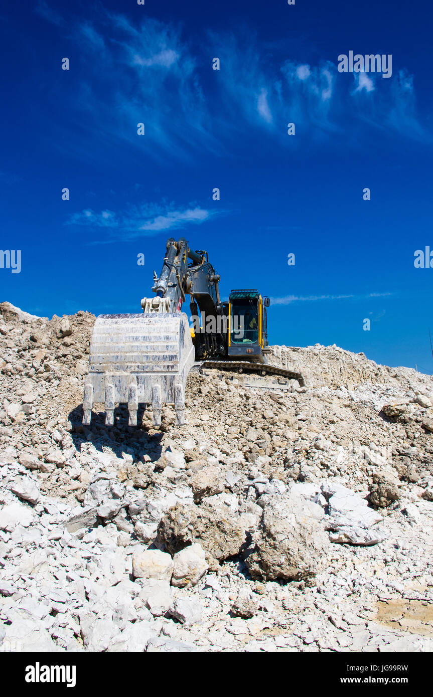 the excavator digging clay on blue sky background Stock Photo - Alamy