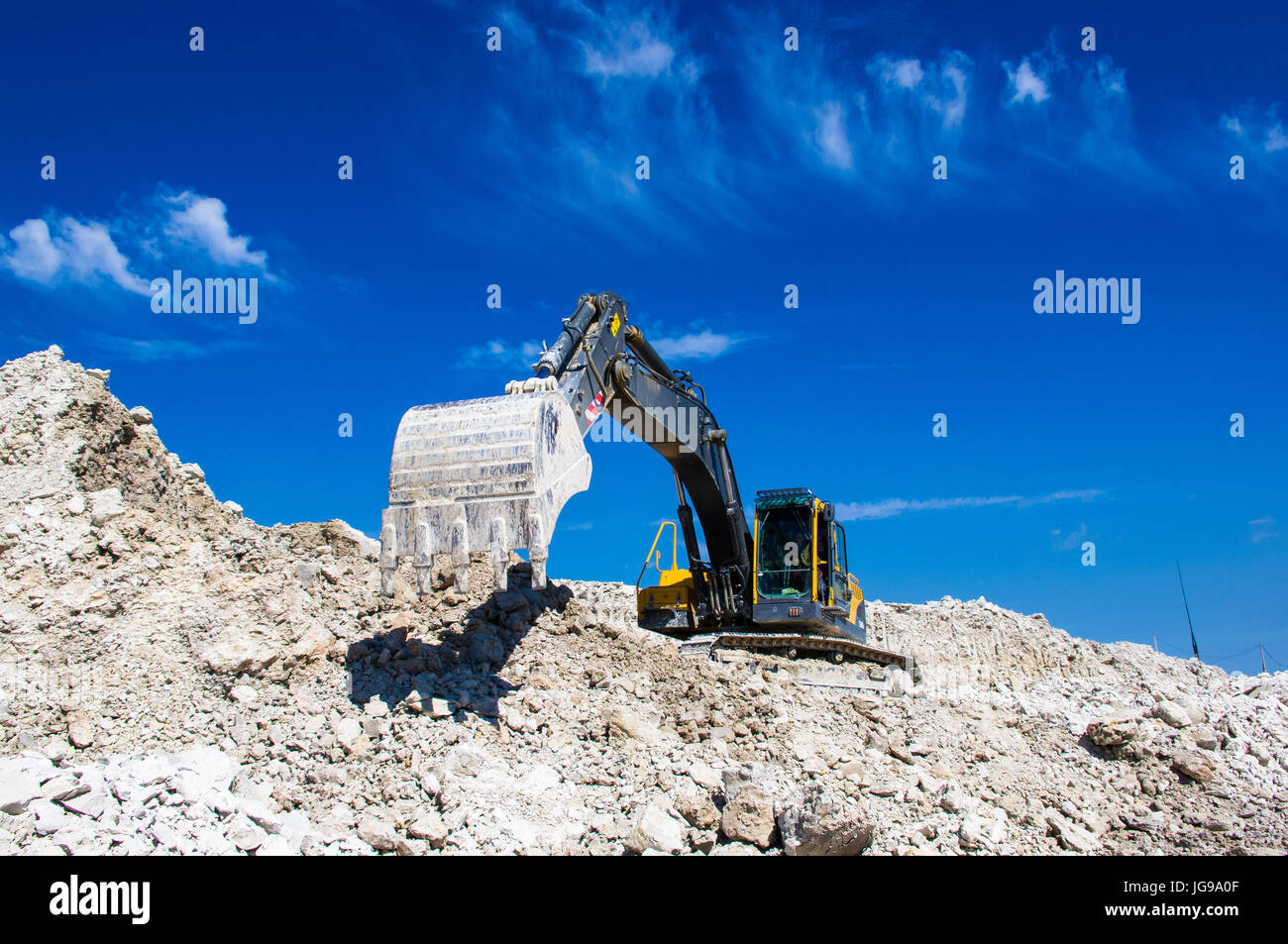 the excavator digging clay on blue sky background Stock Photo - Alamy