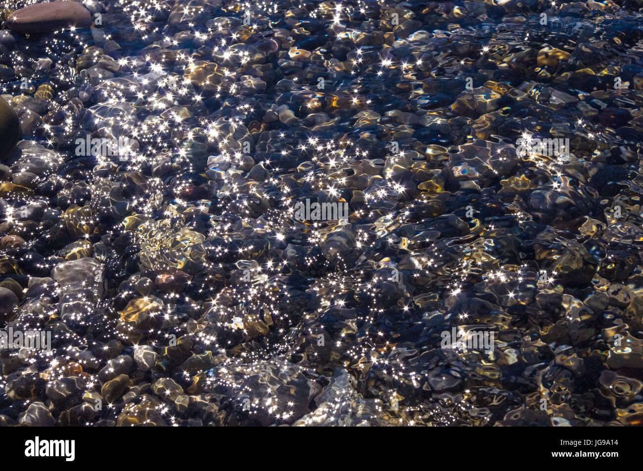 sea pebble beach with multicoloured stones, transparent waves with foam ...