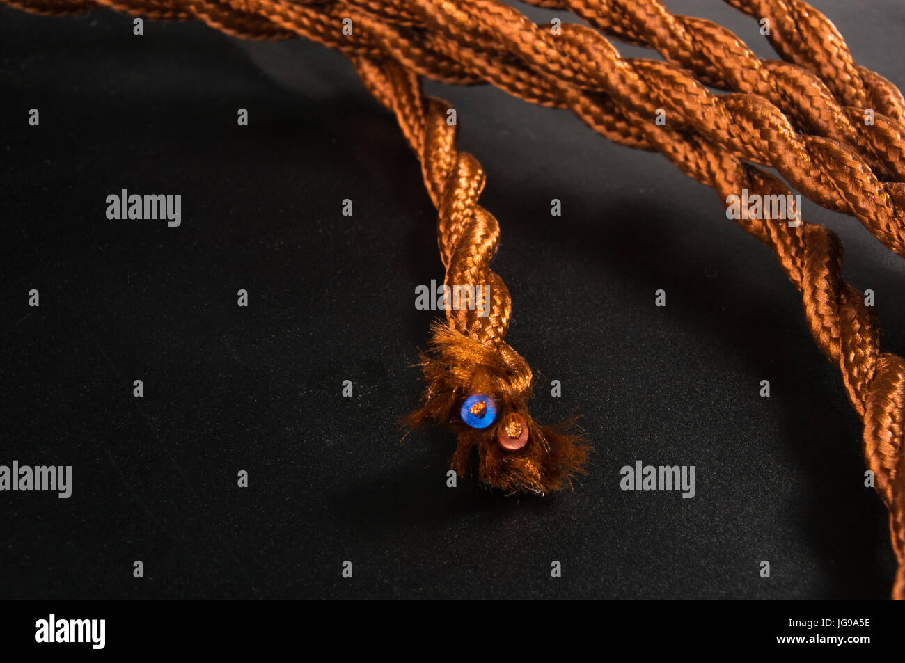 Electric cable in brown braid of fabric in retro style on black ...