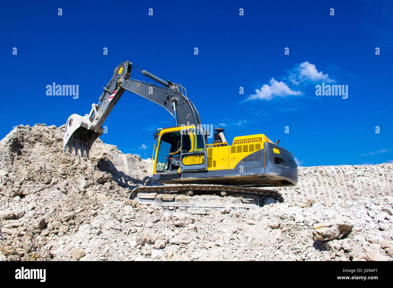 the excavator digging clay on blue sky background Stock Photo - Alamy